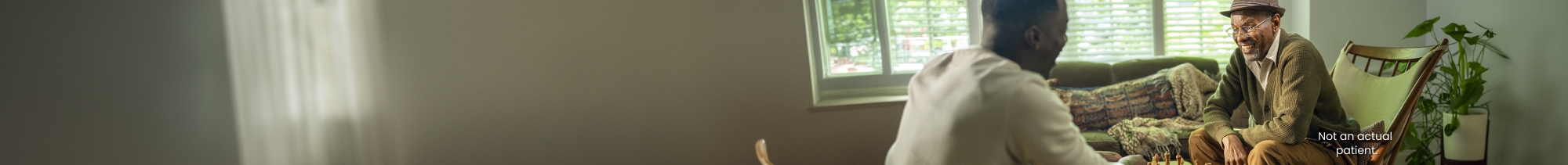 Elderly man talking with younger male while playing chess