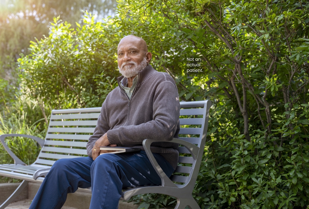 Elderly man smiling and sitting on a park bench